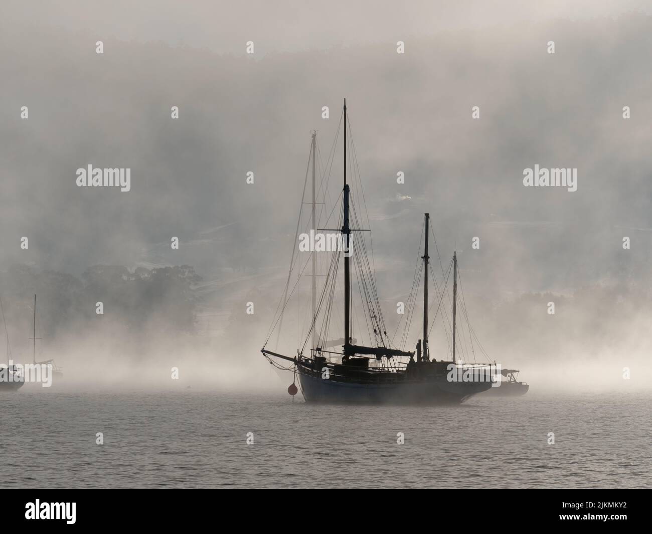 A scenic view of a ship sailing in the ocean and surrounded by fog ...
