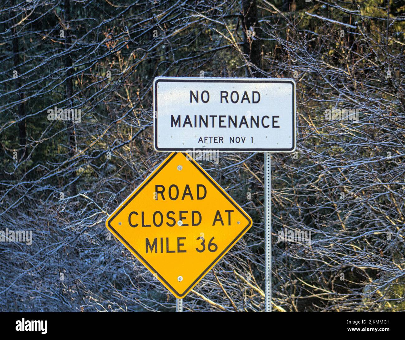 Two no road maintenance warning signboards in the background of tree ...