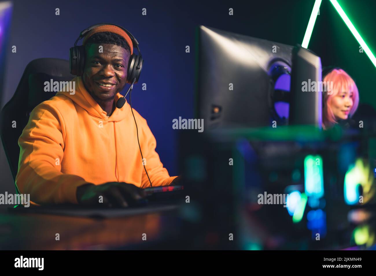 Young black man in orange hoodie wearing headset competing in online ...