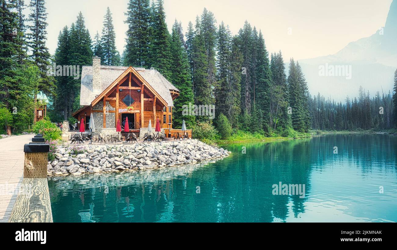 A view of a small country house with a terrace at a lake shore in a ...