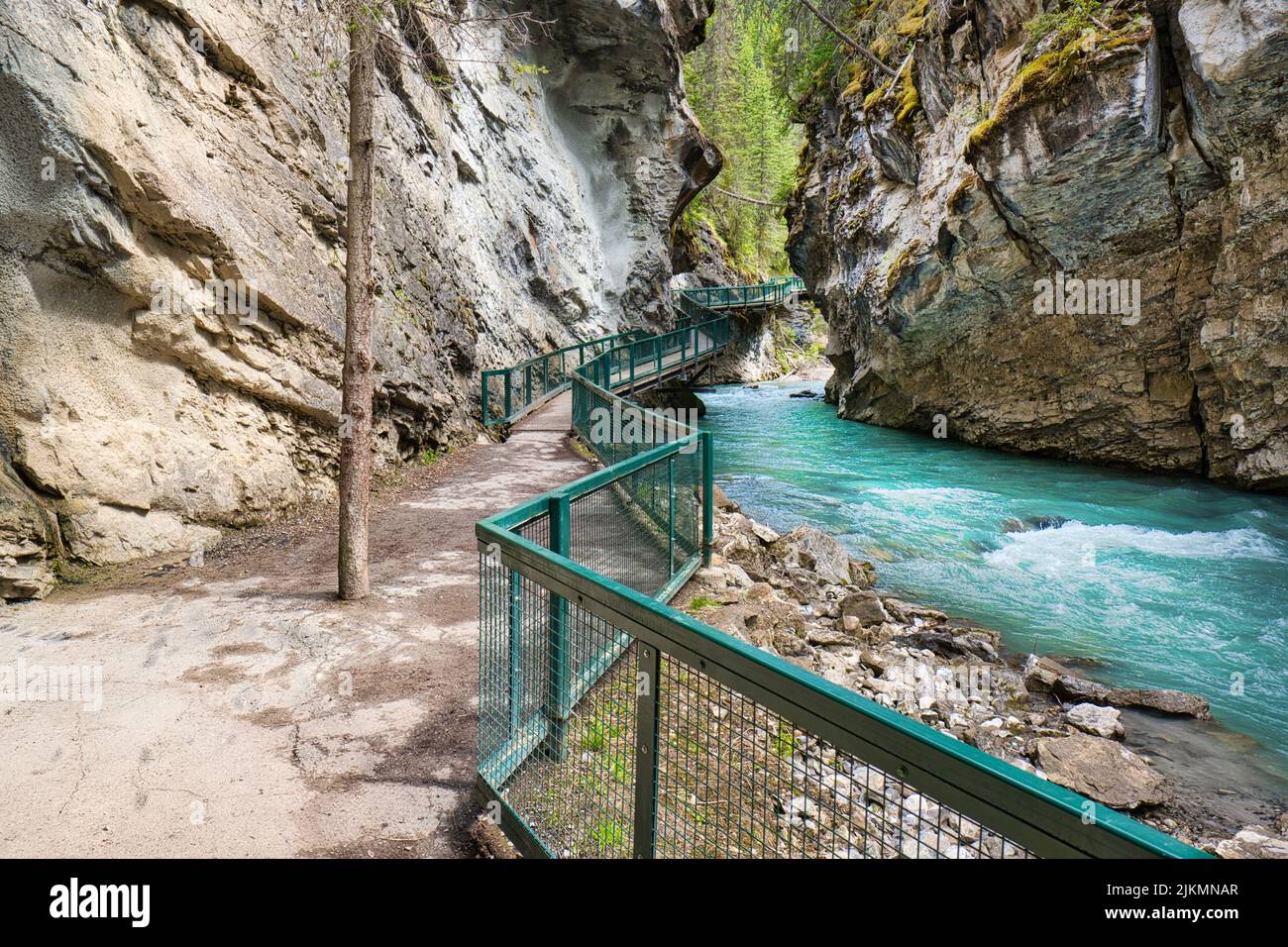 The footpath with green handrails near the river surrounded by cliffs ...