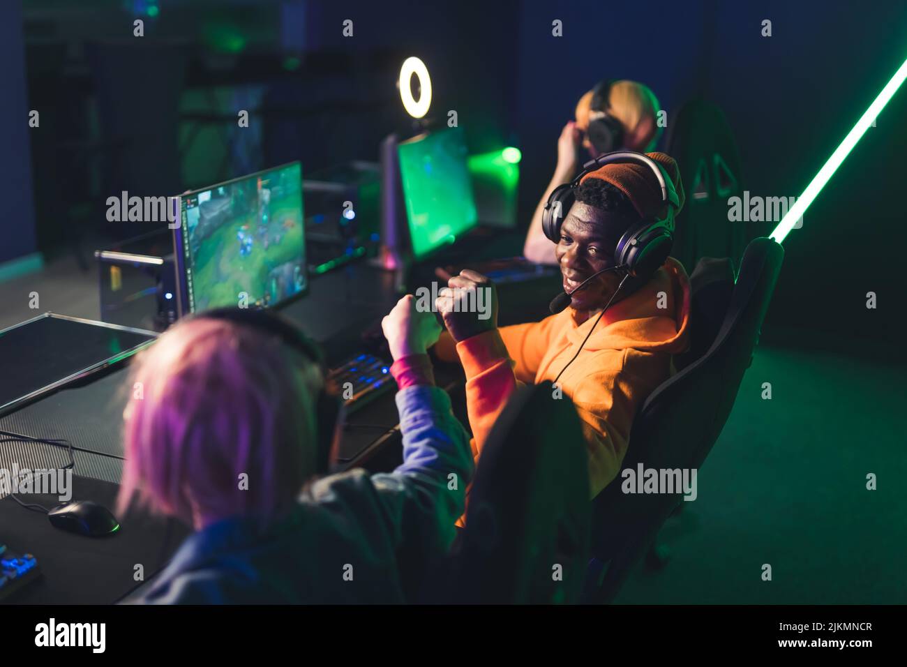 Teenage gamers wearing headsets fistbumping competing in an online ...