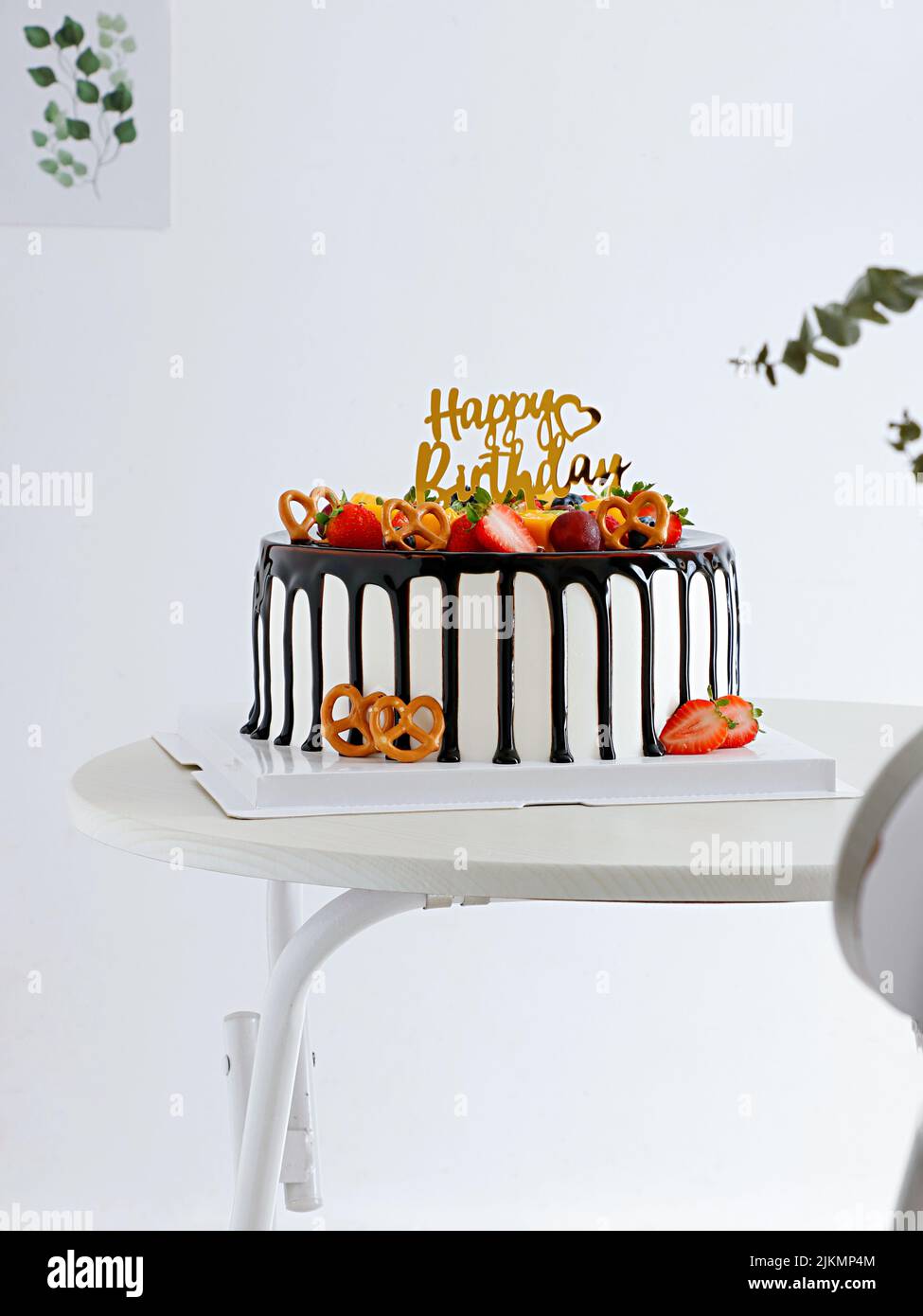 A Cake with chocolate syrup,fruits and a happy birthday sign on a white ...