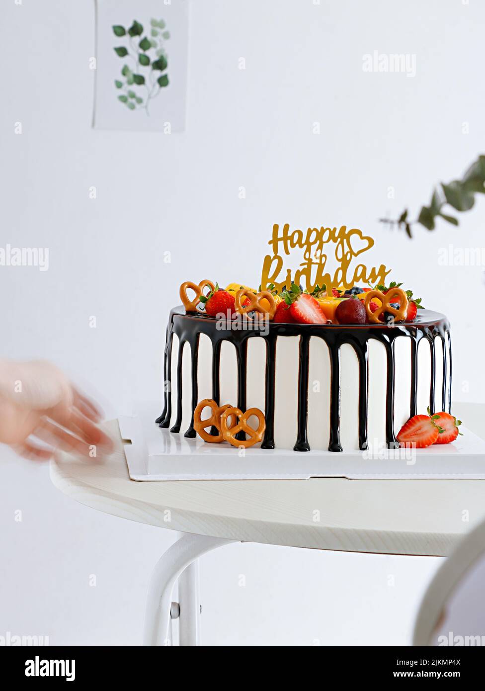 A cake with chocolate syrup,fruits and a happy birthday sign on a white ...