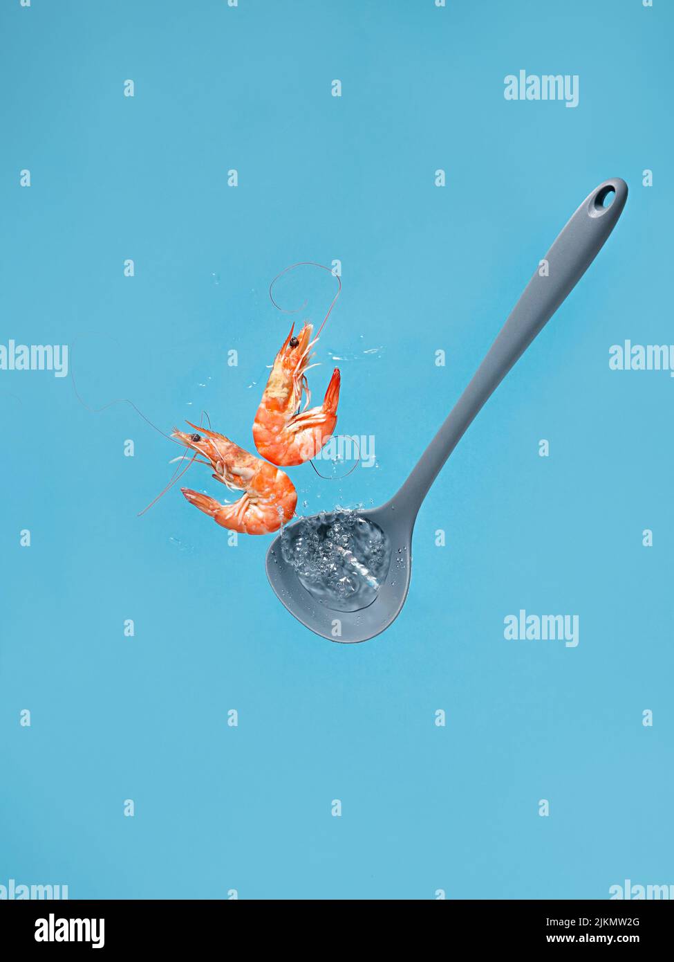 A spoon and shrimp on a blue background - a food poster Stock Photo - Alamy