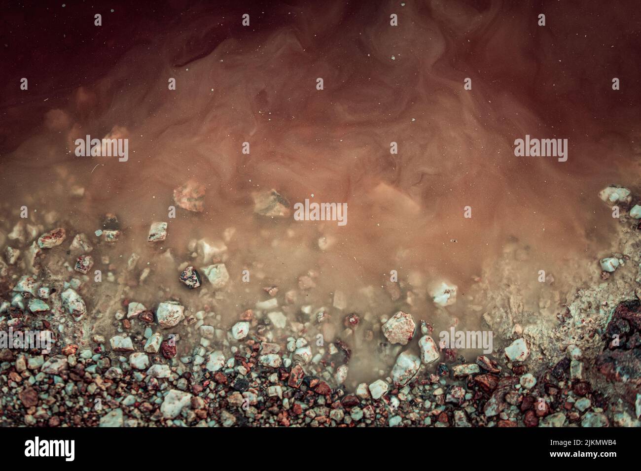 A top view of a stony lakeshore with magical muddy red water - perfect ...