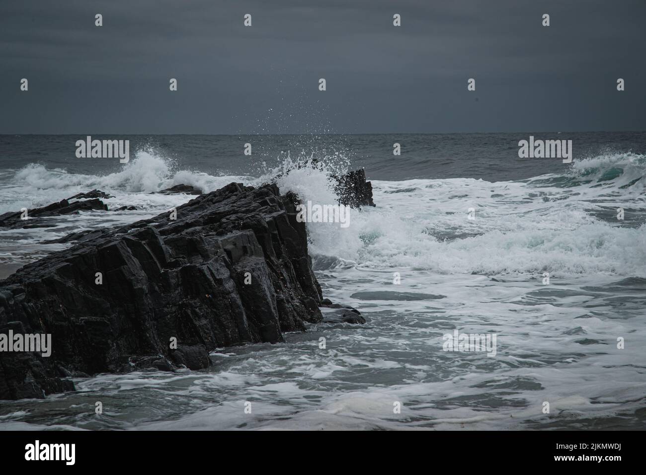 A beautiful view of a sea storm with splashing waves and rocks under a ...