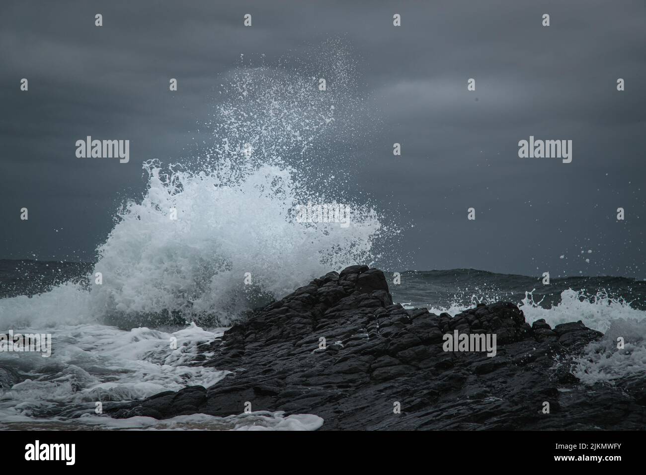 A beautiful view of a sea storm with splashing waves and rocks under a ...
