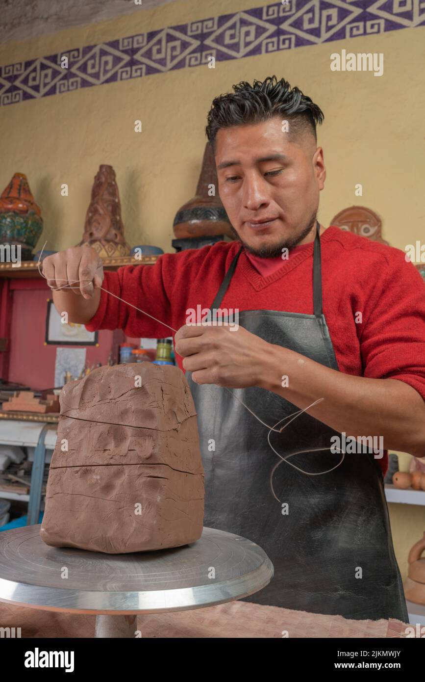Vertical image of a latin potter using a string for the manufacture and ...