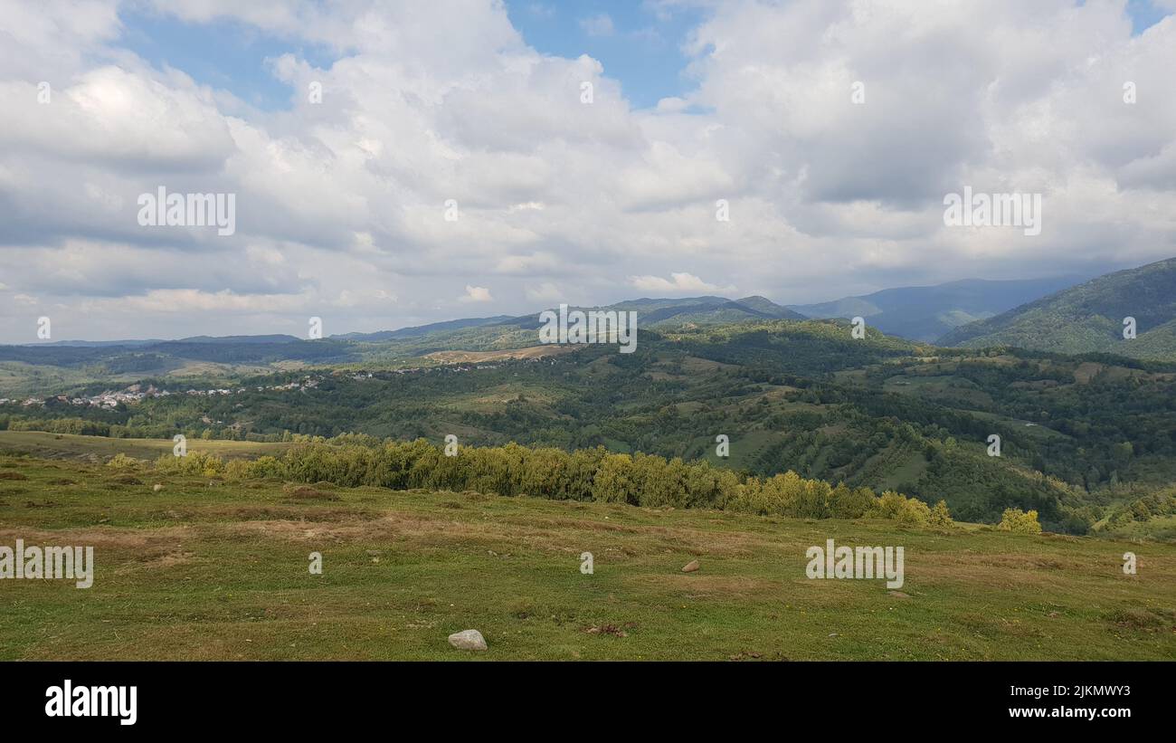 The cloudy sky over the green hills on a calm spring day captured from ...