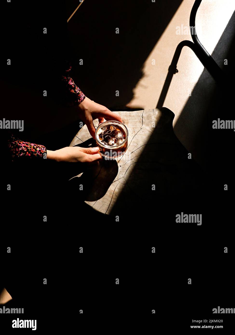 A female hand taking a cup of refreshing iced coffee from the wooden ...