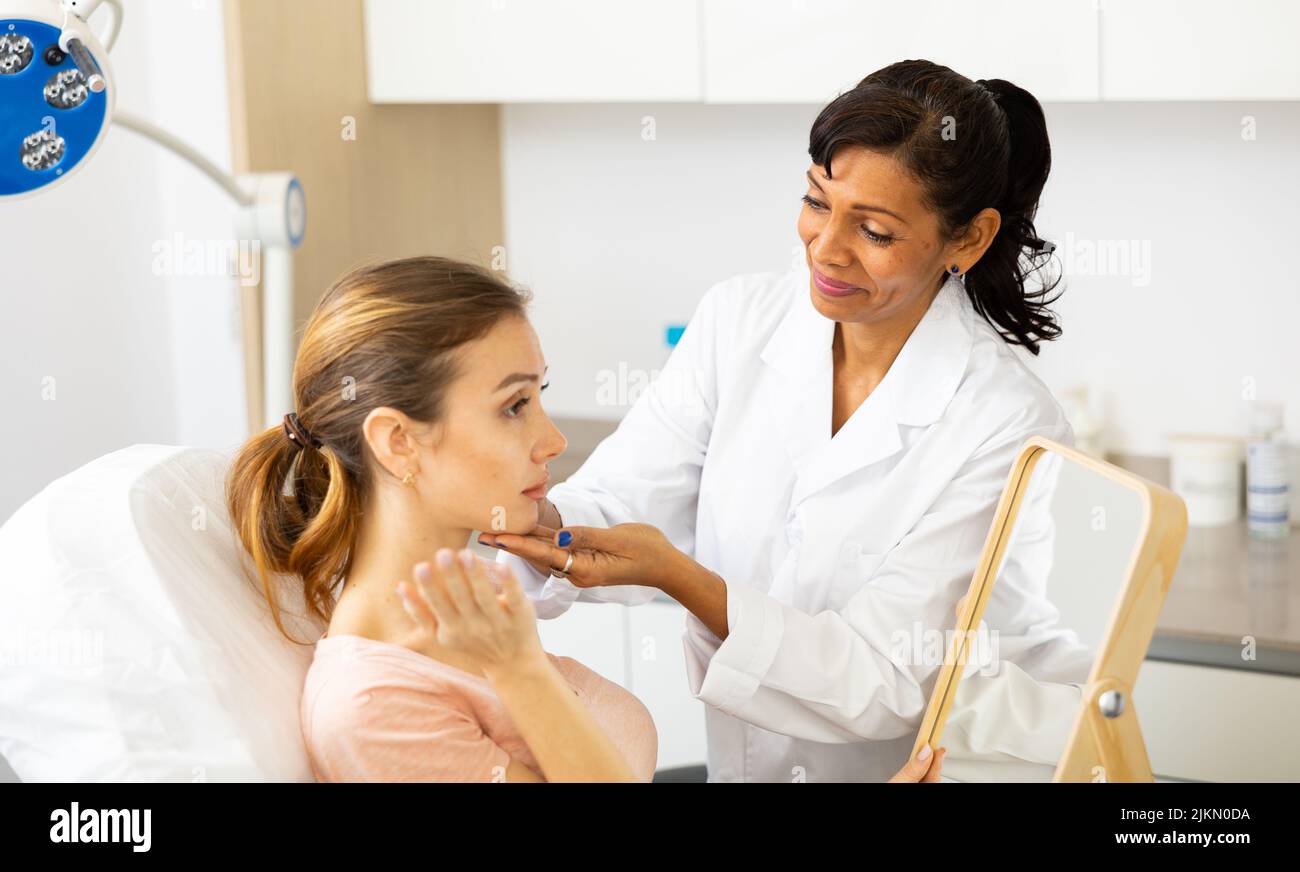 Female beauty doctor looking at woman's face during examination Stock ...