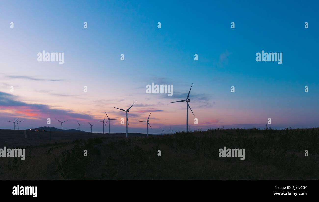 A scenic view of windmills on a vast landscape during sunset Stock ...