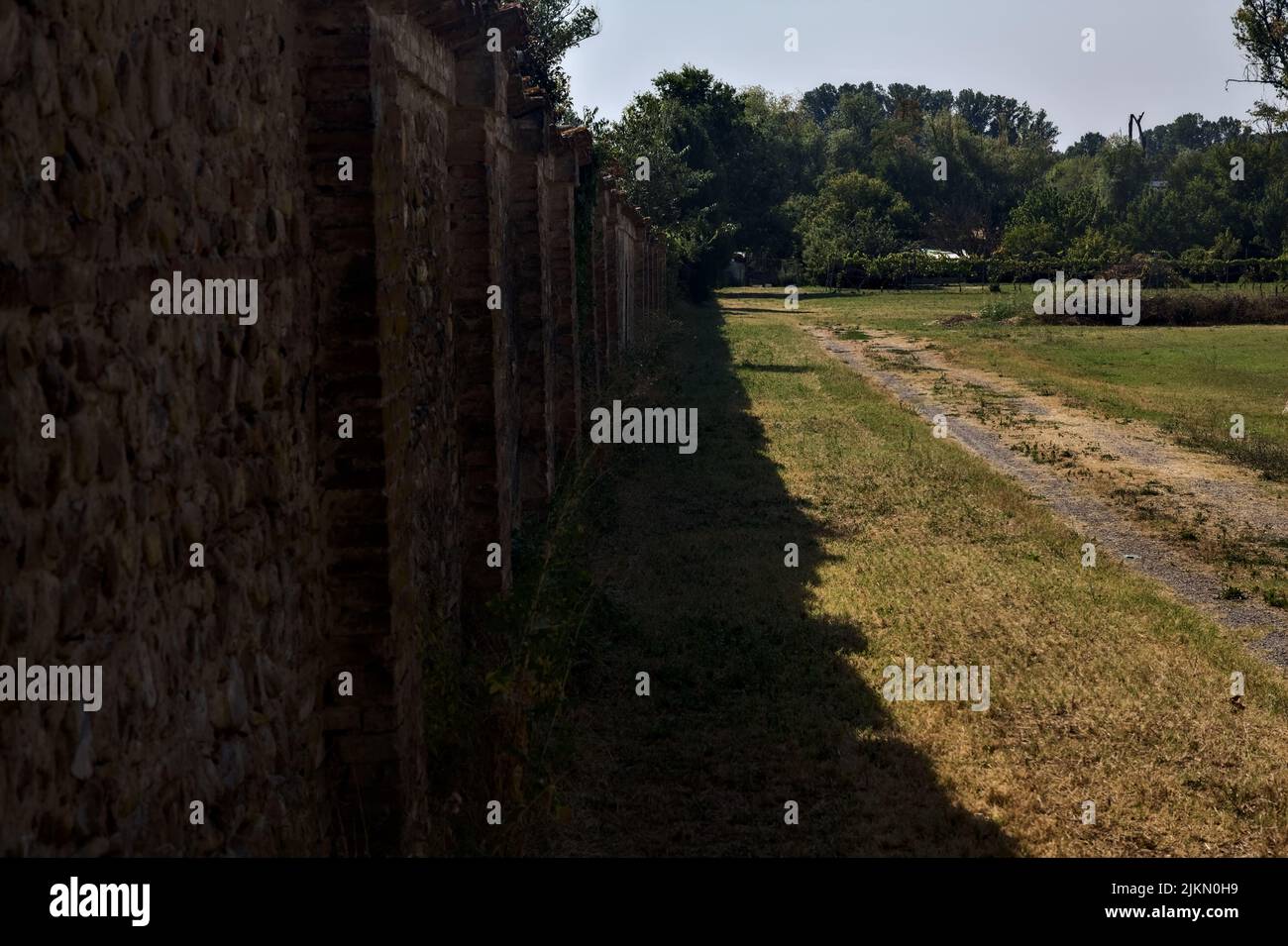 Dirt path next to a boundary wall in a park on a sunny day Stock Photo ...