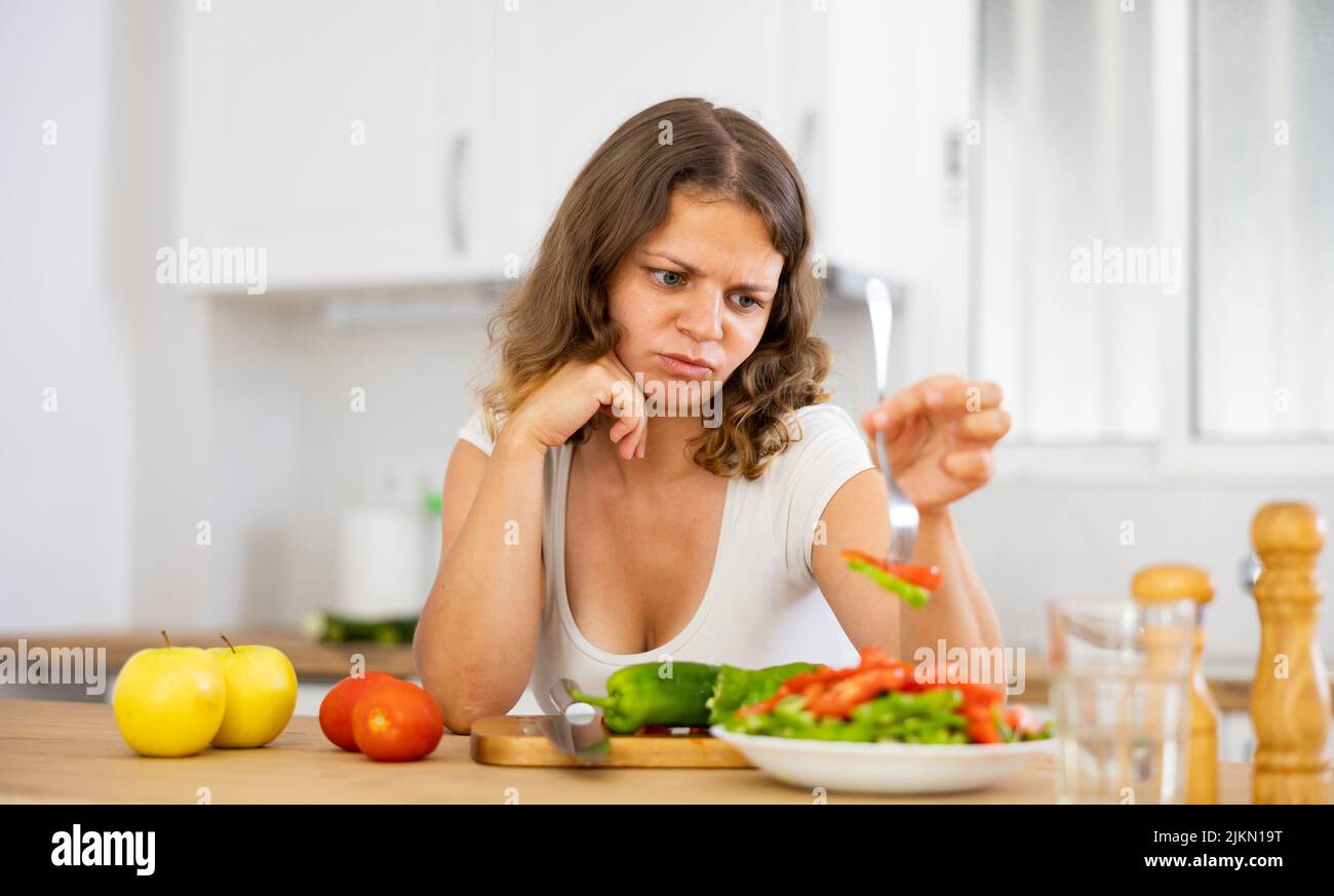 Portrait of sad woman eating salad at home Stock Photo - Alamy