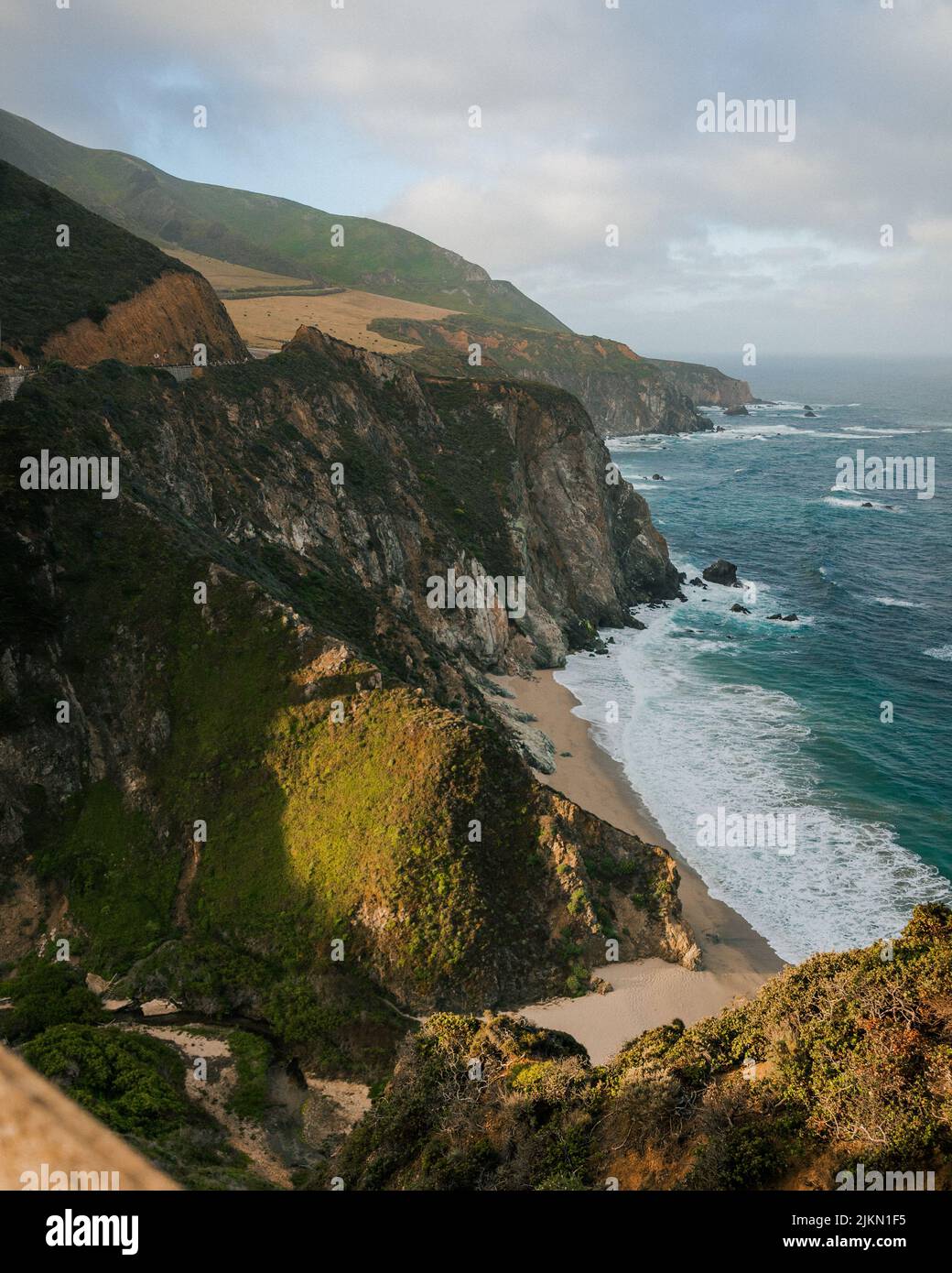 A vertical high angle shot of the ocean waves hitting the coast with ...