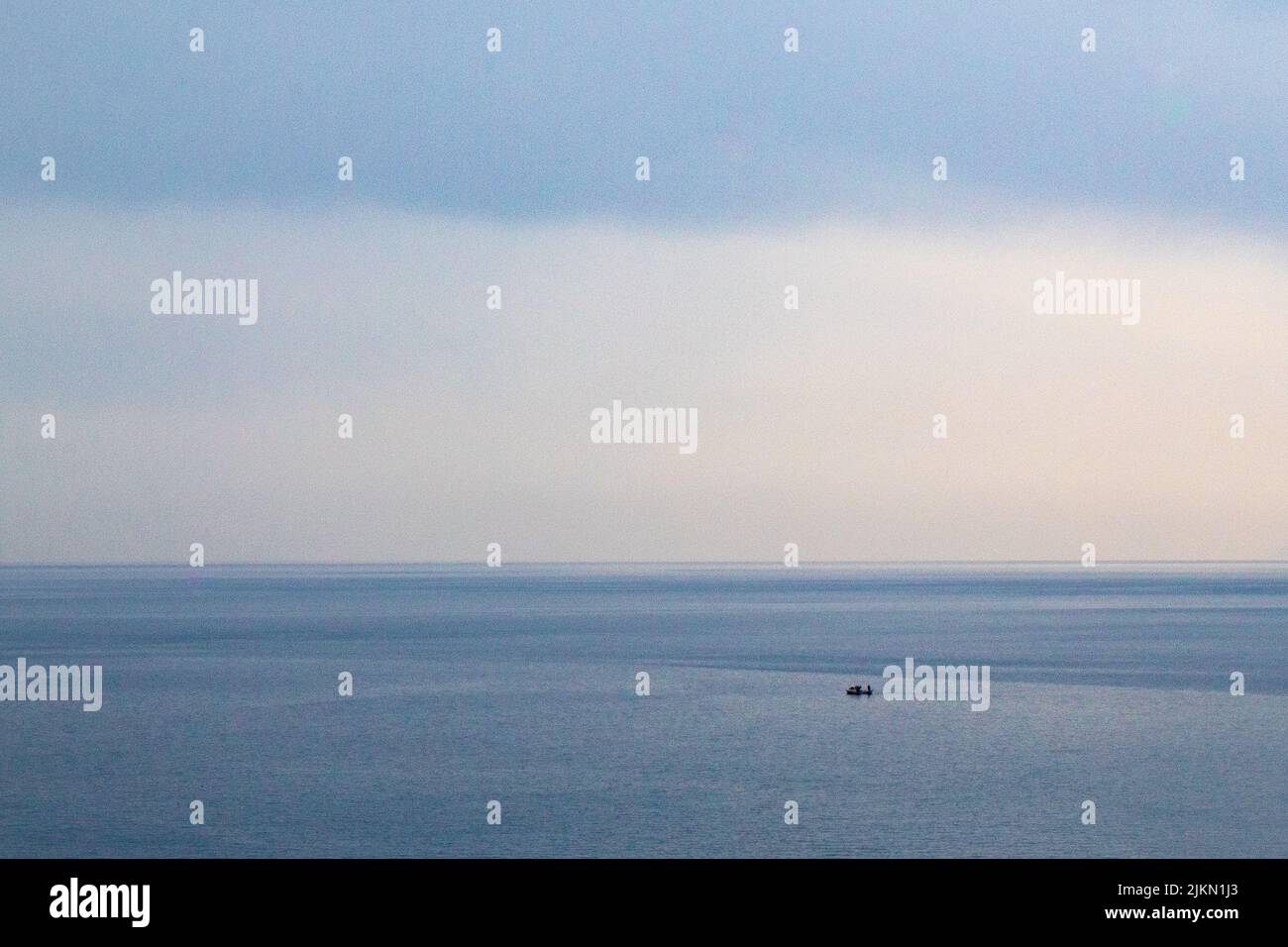 A single boat far away in the sea water Stock Photo - Alamy