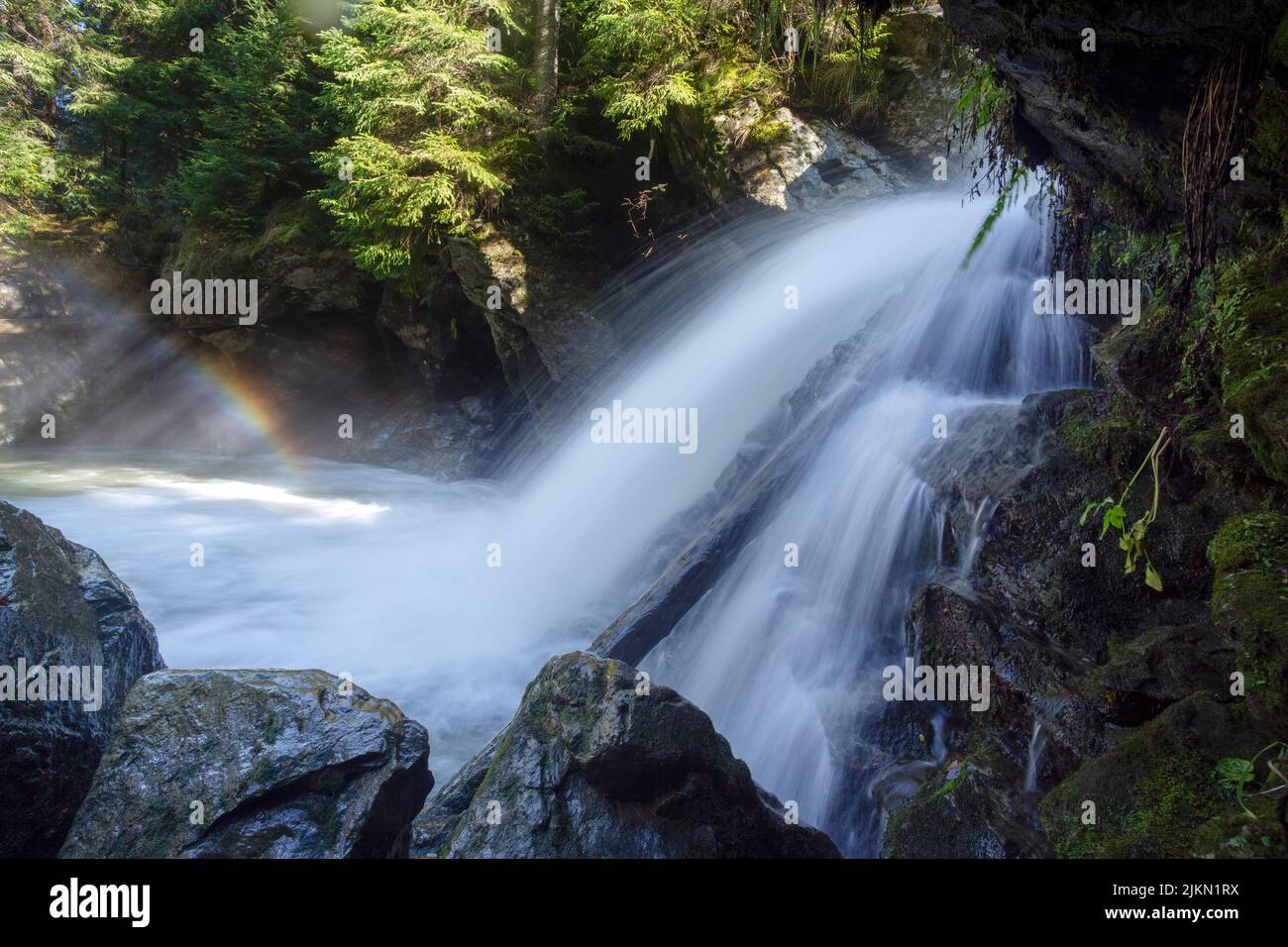 A scenic view of the waterfall splashes and a rainbow against the ...
