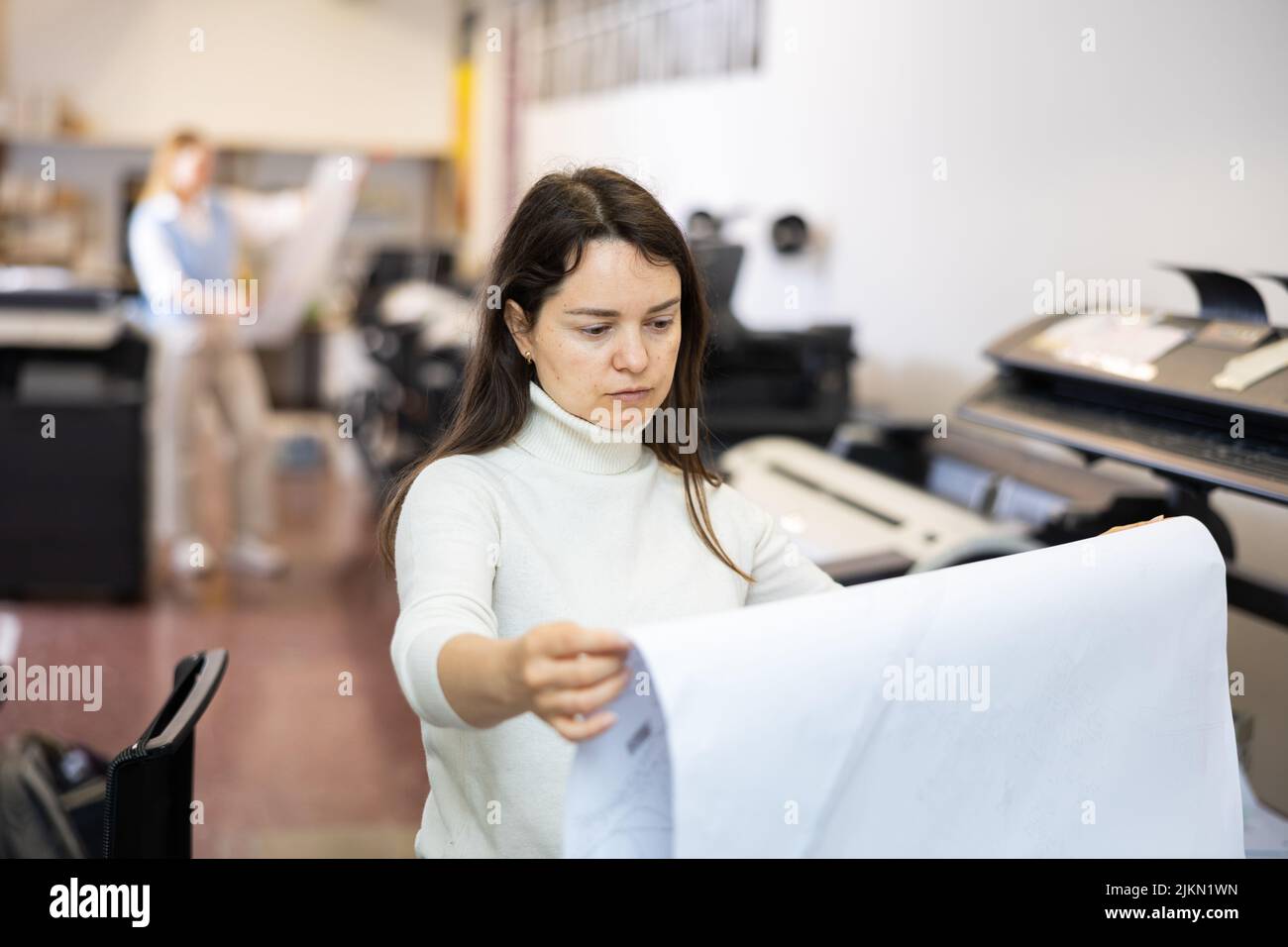 Printing establishment worker examining large piece of paper Stock ...