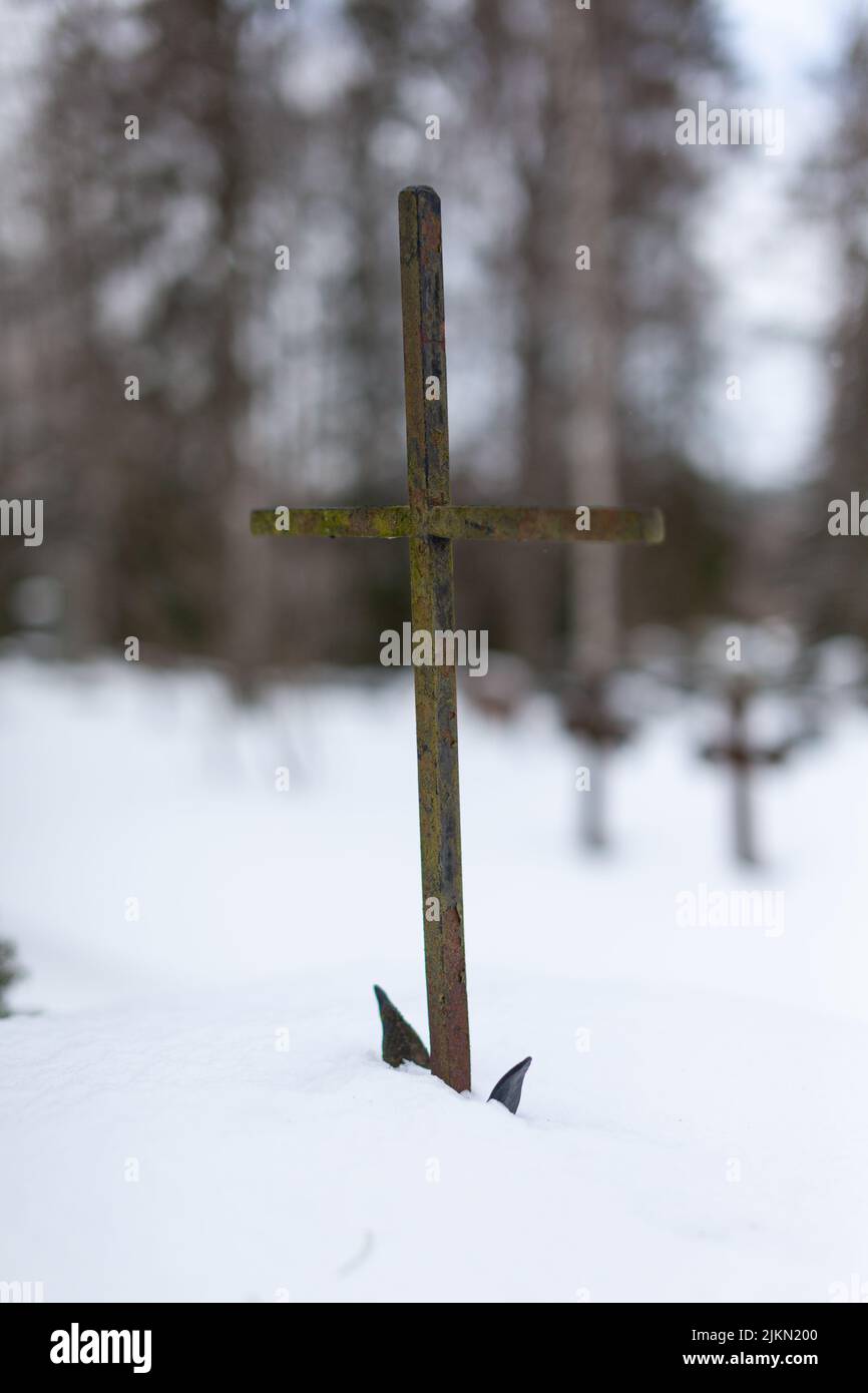 A vertical shot of an iron cross pinched in a snow on a blurred ...