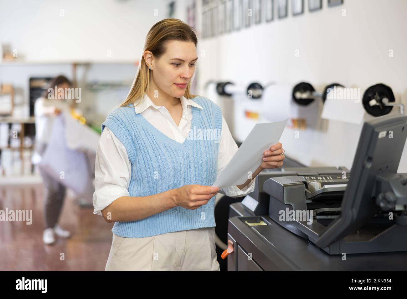 Woman checking paper after printing Stock Photo - Alamy