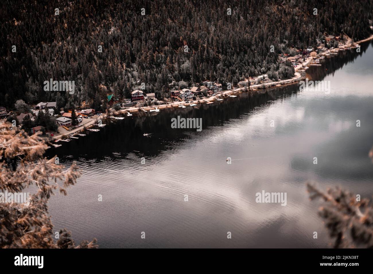 An aerial view of calm lake water with forest trees and buildings by ...