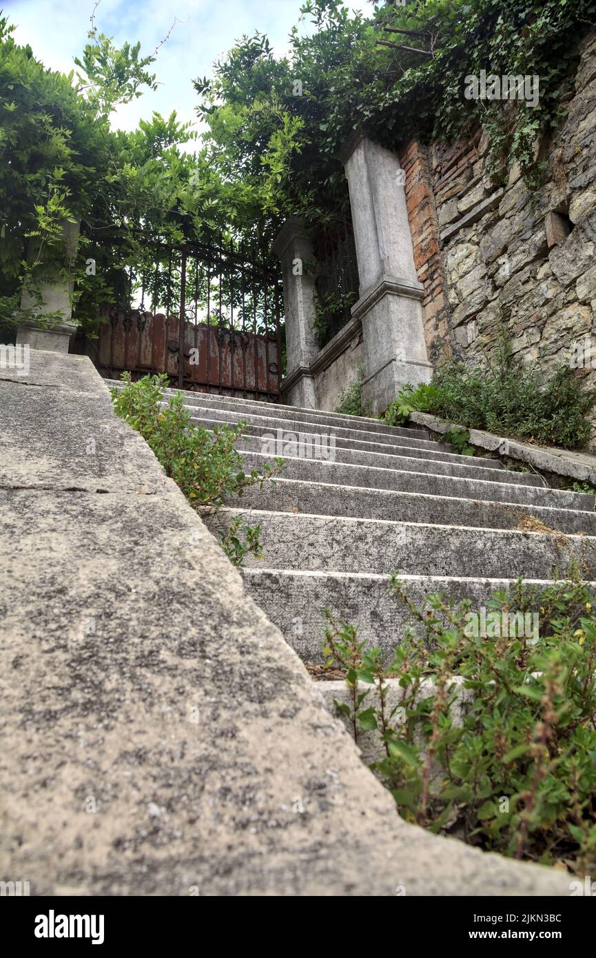 Worn stone staircase that leads to a rusty gate next to a stone wall on ...