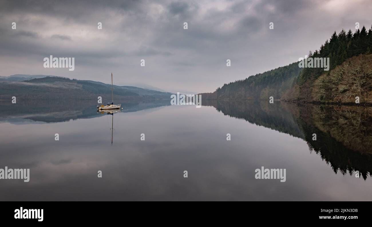 A beautiful landscape with a boat reflected in the water at Loch Lee ...