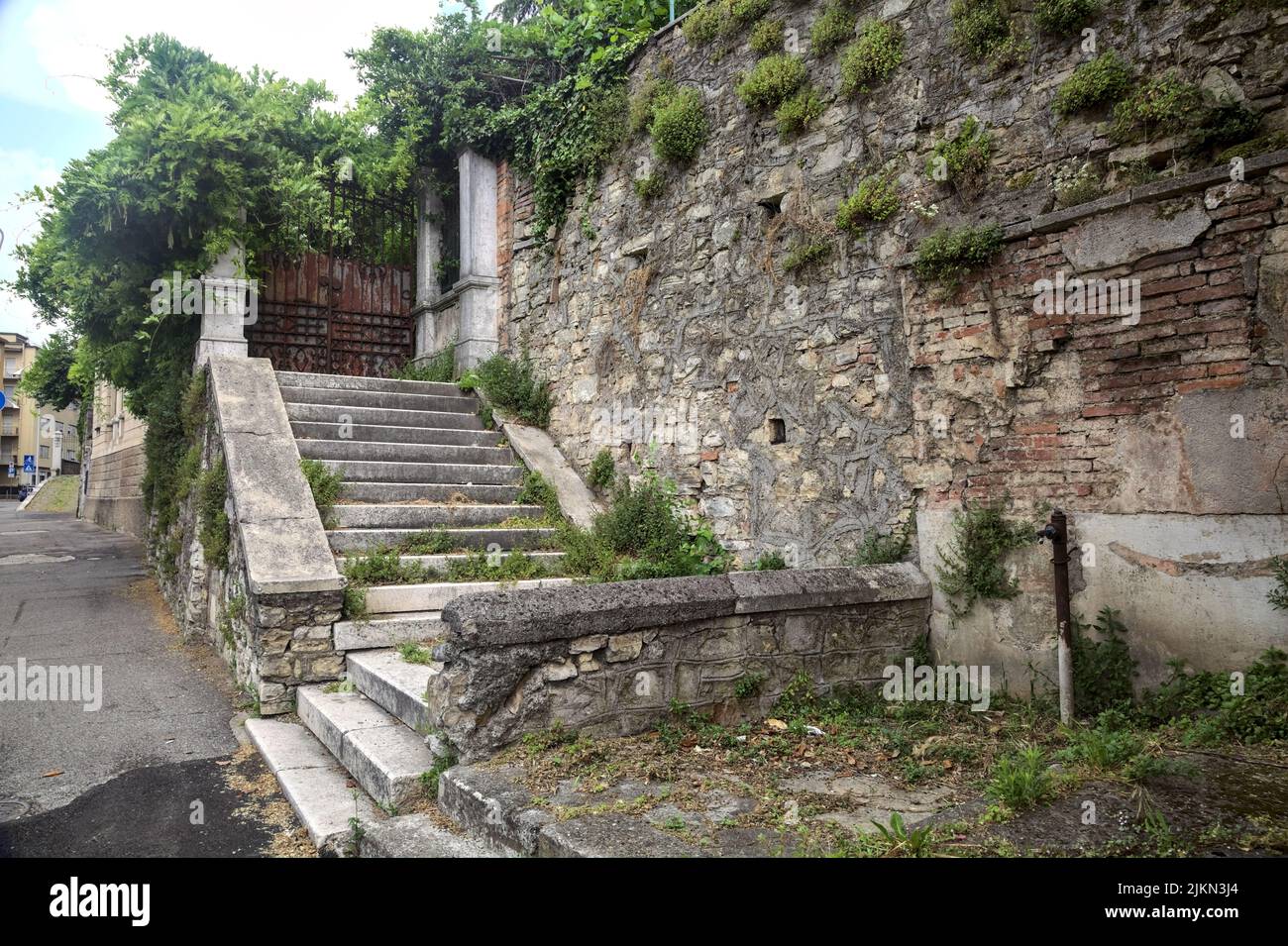 Worn stone staircase that leads to a rusty gate next to a stone wall on ...
