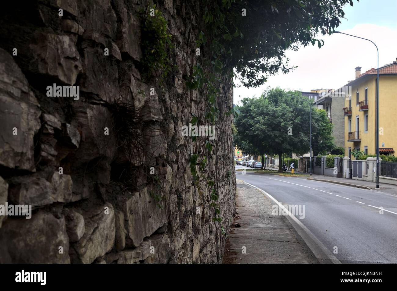 Pavement by the edge of a road and next to a stone wall Stock Photo - Alamy