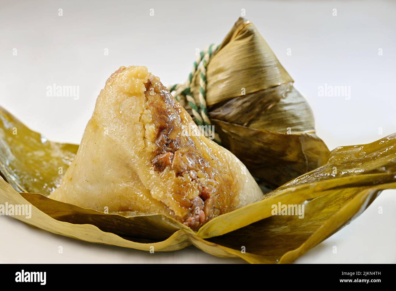 A Chinese sticky rice zongzi or bakcang, wrapped in bamboo leaves, and ...