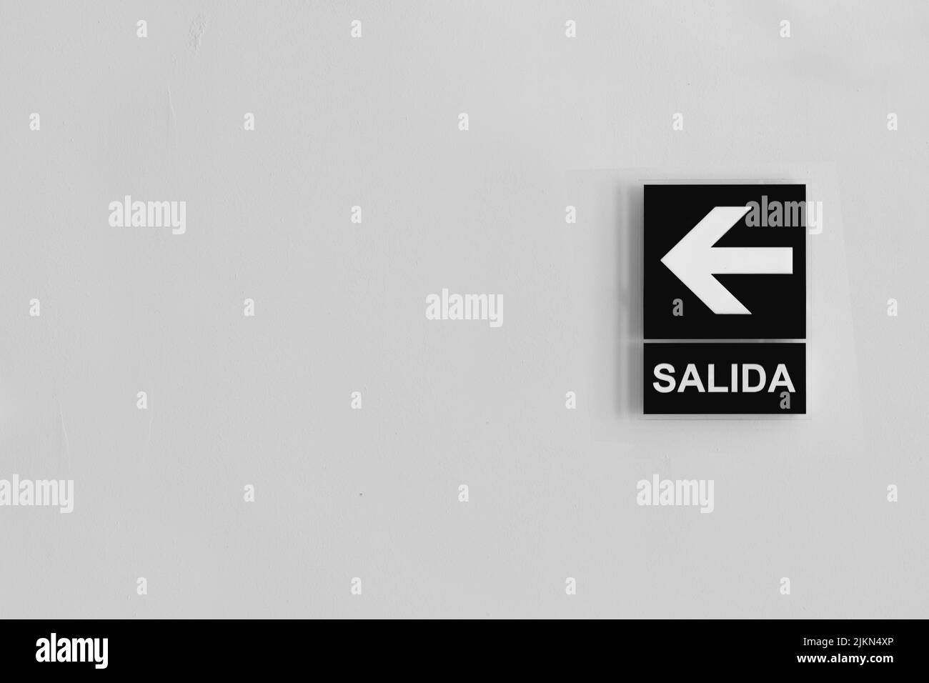 A grayscale exit (SALIDA) sign in Spanish with left arrow Stock Photo ...