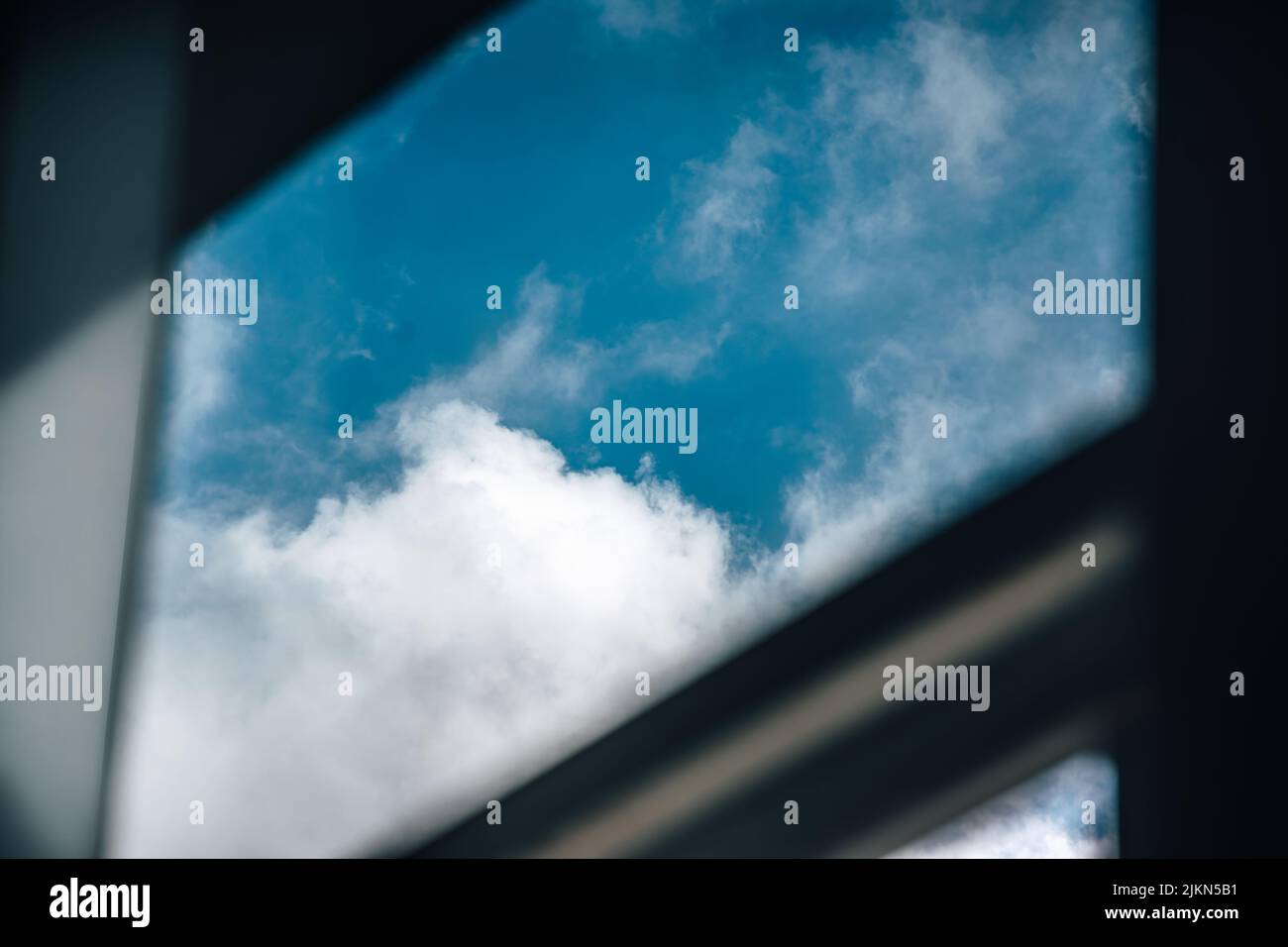 A low angle shot of white clouds and blue sky from between the windows ...
