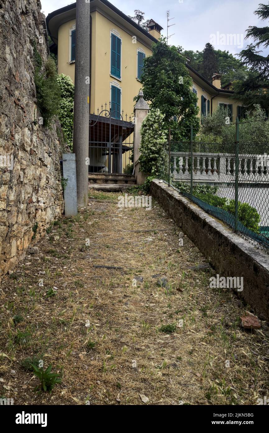Uphill dirt path next to a wall that leads to a gate of a house Stock ...