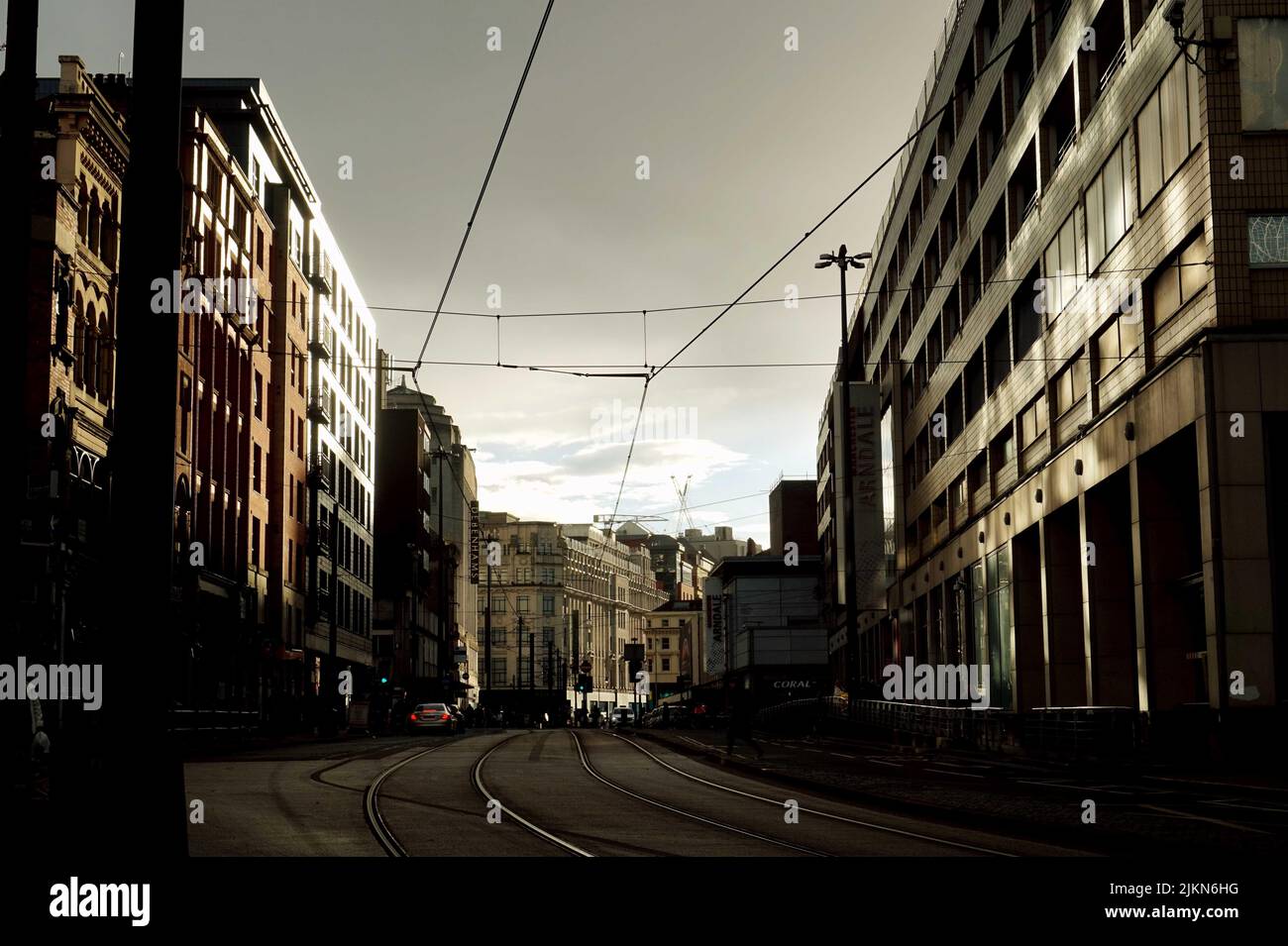 A gloomy shot of Manchester city center with tram lines under the ...