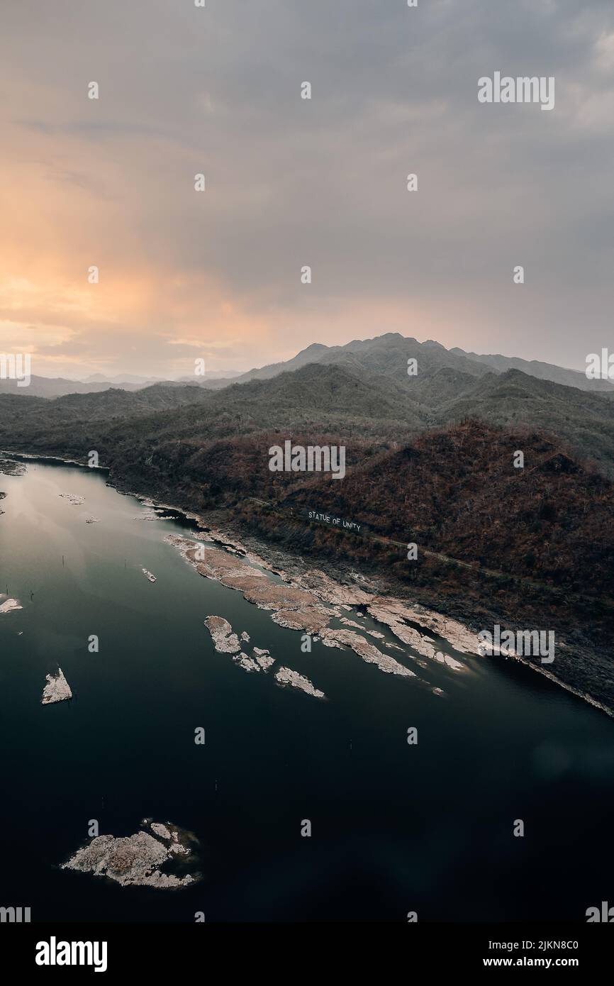 A high angle shot of seawater sea with hills and text of STATUE OF ...