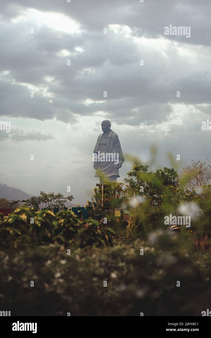 A vertical shot of a statue of Unity in India against a cloudy sky ...