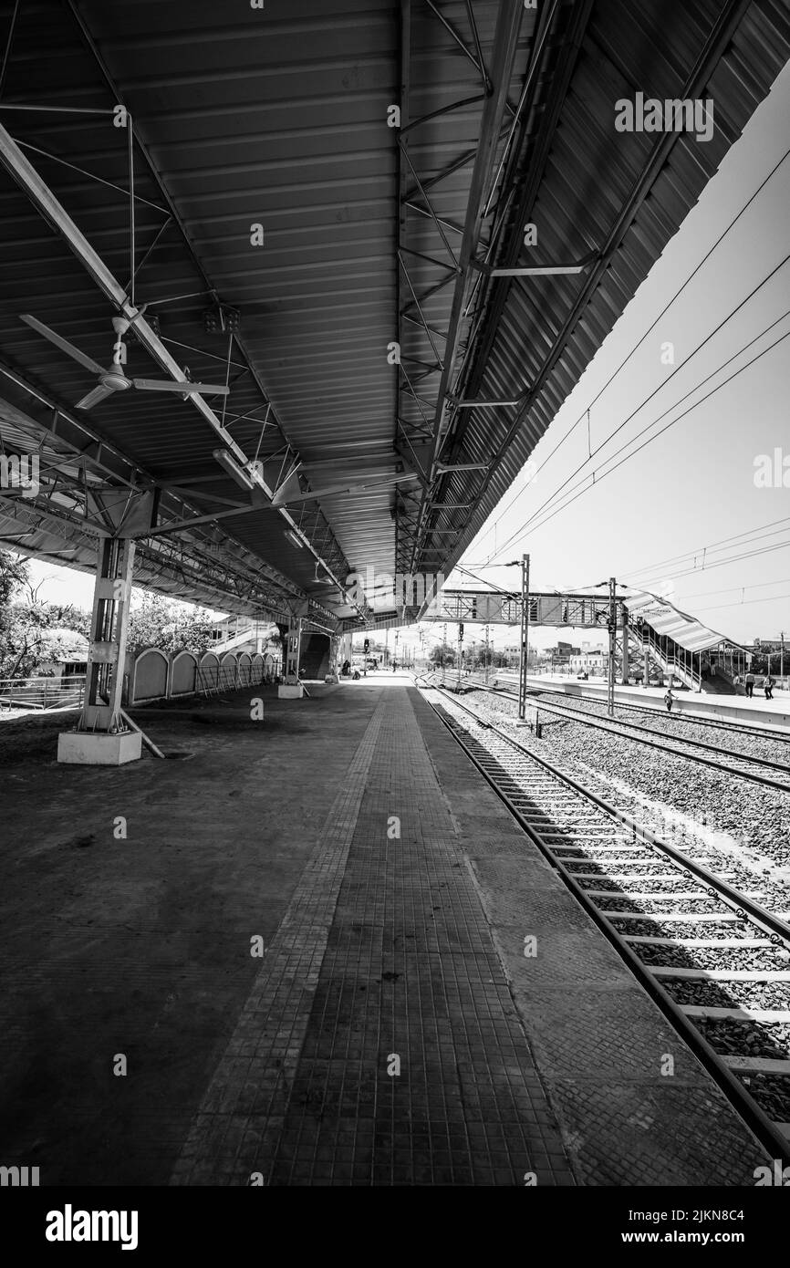 A vertical shot of an empty train station on a sunny day in grayscale Stock Photo - Alamy