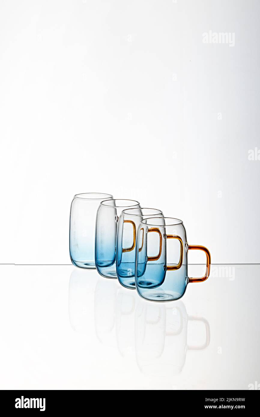 The vertical shot of a glass blue transparent cups with a white ...