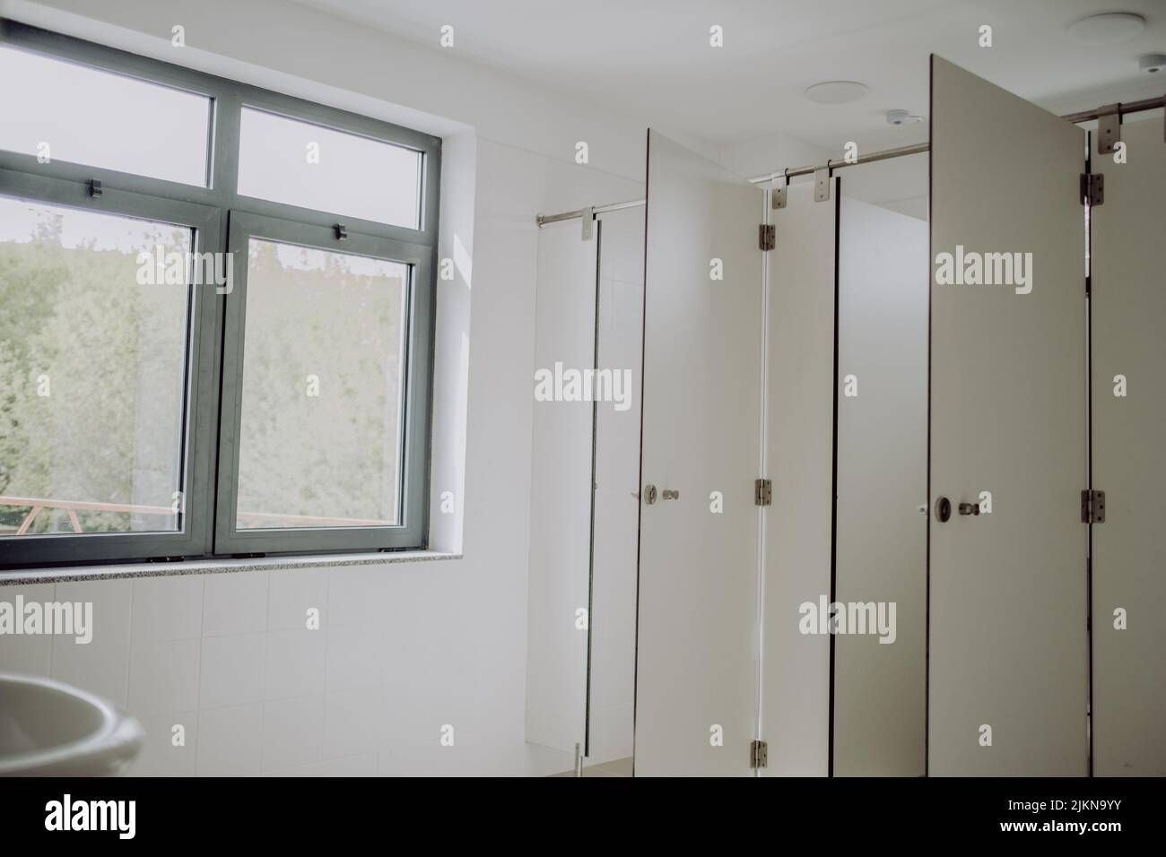 A toilet partitions near a glass window in a comfort room Stock Photo ...