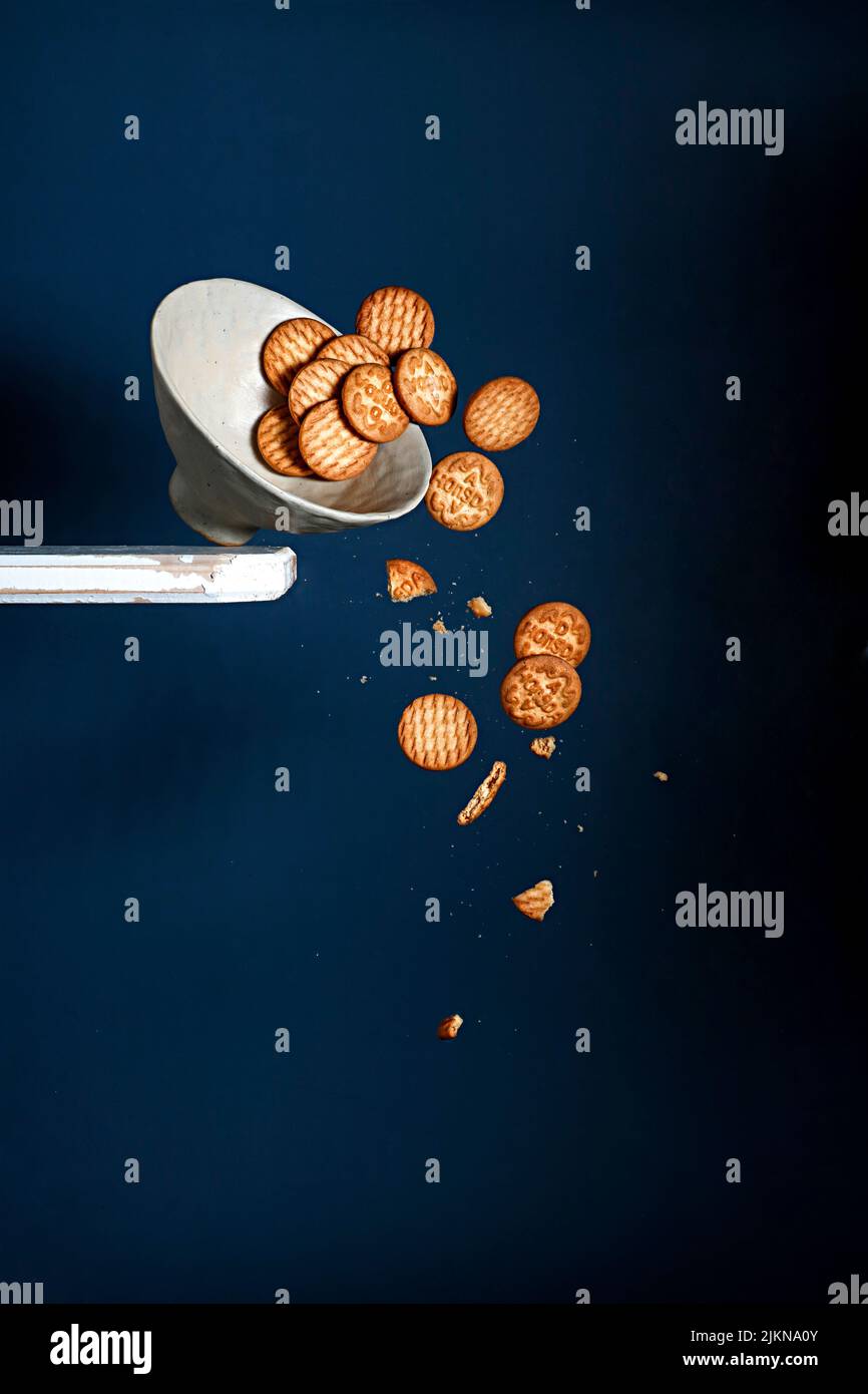 the Studio shot of Cookies falling from a bowl isolated on a blue ...