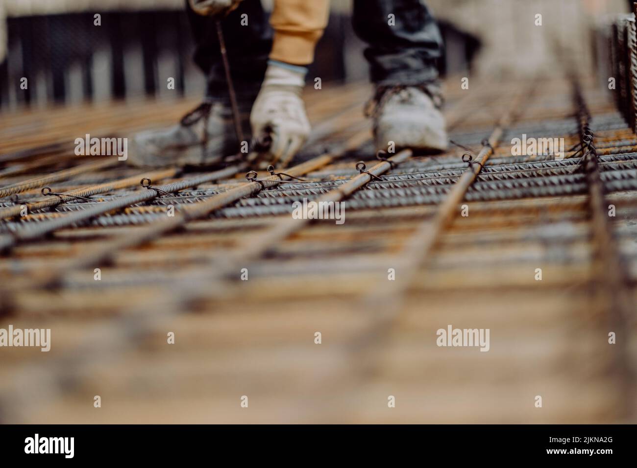 A selective focus shot of a worker on a rusty concrete reinforcement ...
