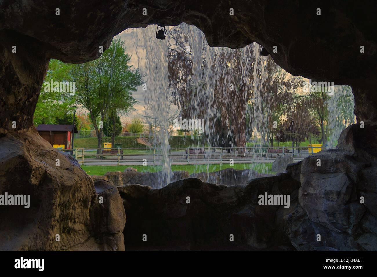 A silk effect water falling down in a park seen through a stone cave ...