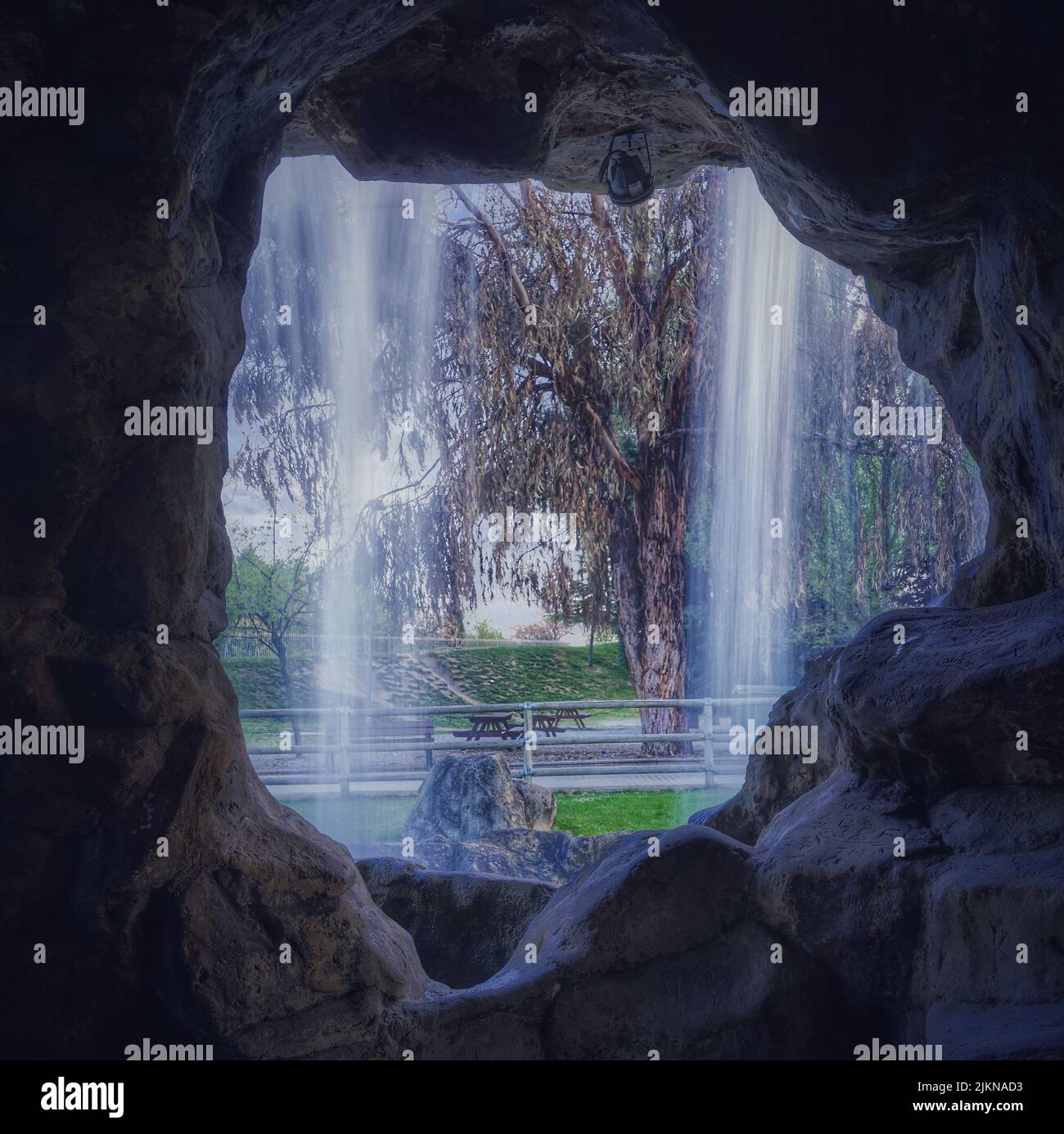 A silk effect water falling down in a park seen through a stone cave ...