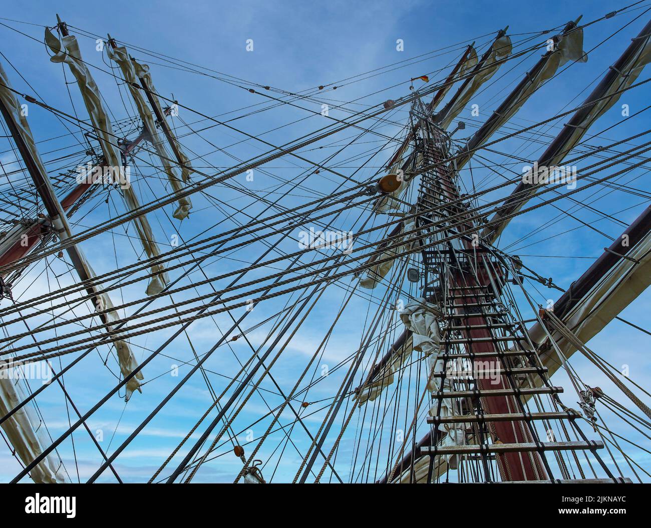 The tall mast of an old sailing ship with a ship's cable ladder in the ...