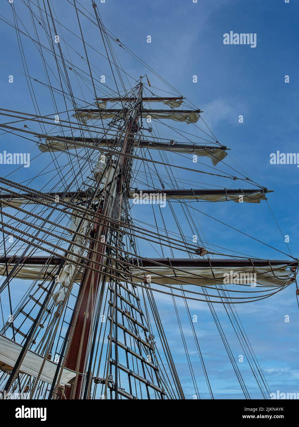 The tall mast of an old sailing ship with a ship's cable ladder in the ...
