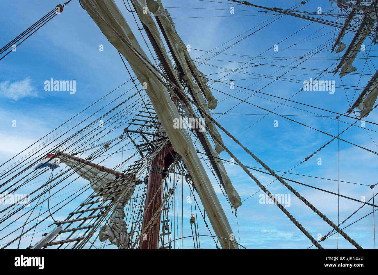 The tall mast of an old sailing ship with a ship's cable ladder in the ...