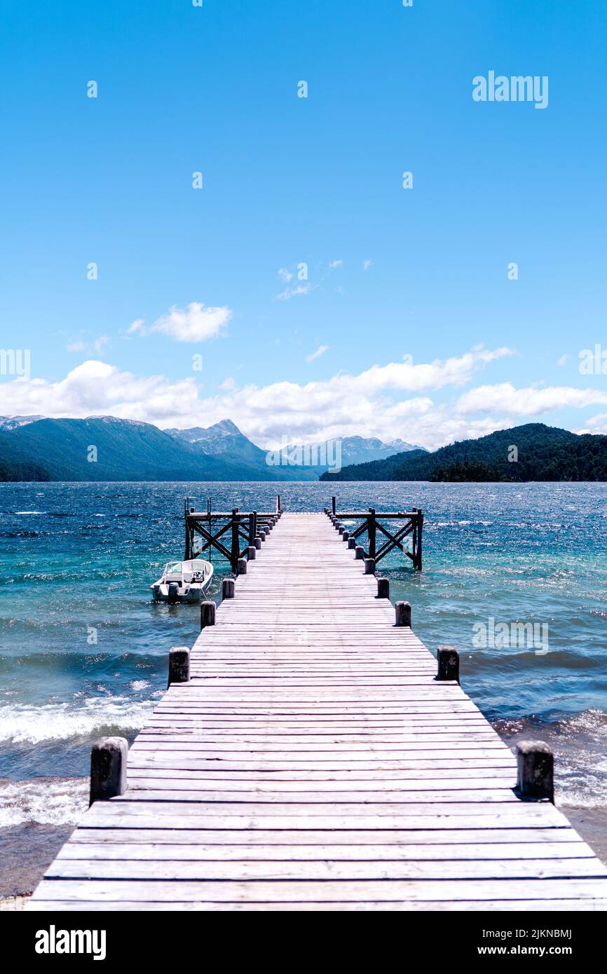 A beautiful scene of a wooden pier on the water by misty mountains and ...