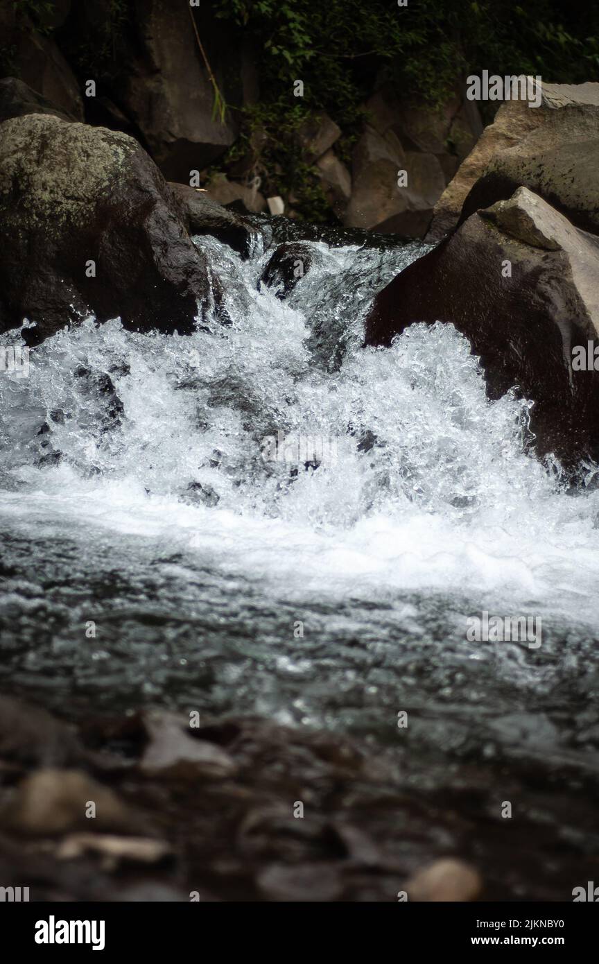 A vertical shot of a water doing splash with hitting the rocks Stock ...