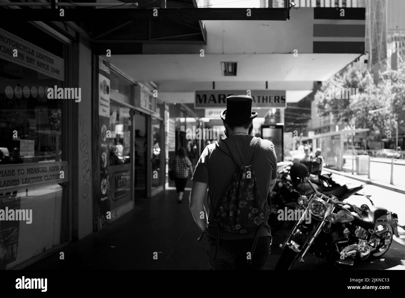A grayscale closeup of the man walking down the street in a top hat ...